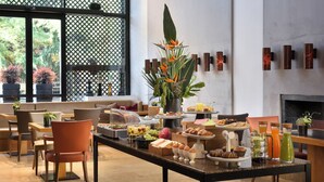 Espaço de refeições com buffet, disposição de assentos e vista através de grandes janelas.