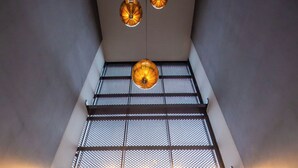 Interior moderno com teto alto, persianas estampadas e área de estar com vista para o verde lá fora.
