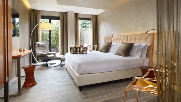 Quarto de hotel moderno com uma cama grande, uma escrivaninha, uma cadeira e uma janela com cortinas.