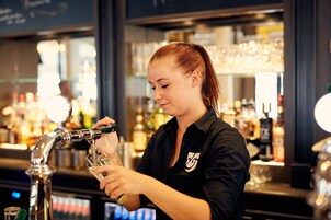 Um bartender servindo uma bebida de uma torneira.