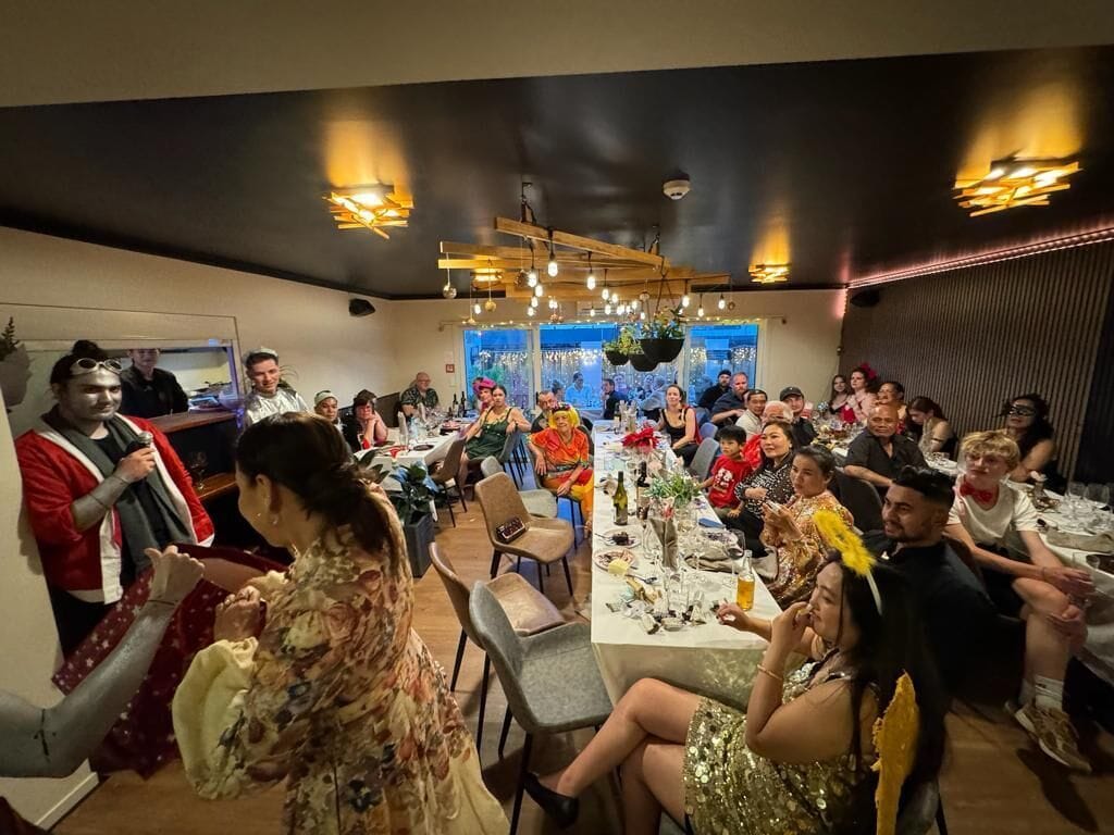 Um grupo de pessoas sentadas à mesa em espaço interno bem iluminado, com luminárias pendentes e design moderno no teto.