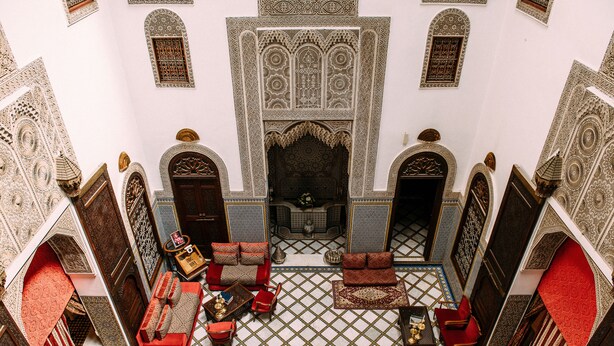 Um interior luxuoso com teto alto, arcos ornamentados e piso estampado.
