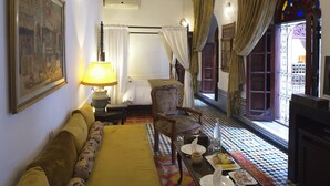 Quarto tradicional com sofá, poltrona e mesa com abajur.