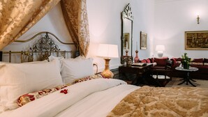 Um quarto com uma cama grande, uma escrivaninha com uma lâmpada, um sofá vermelho e um espelho na parede.