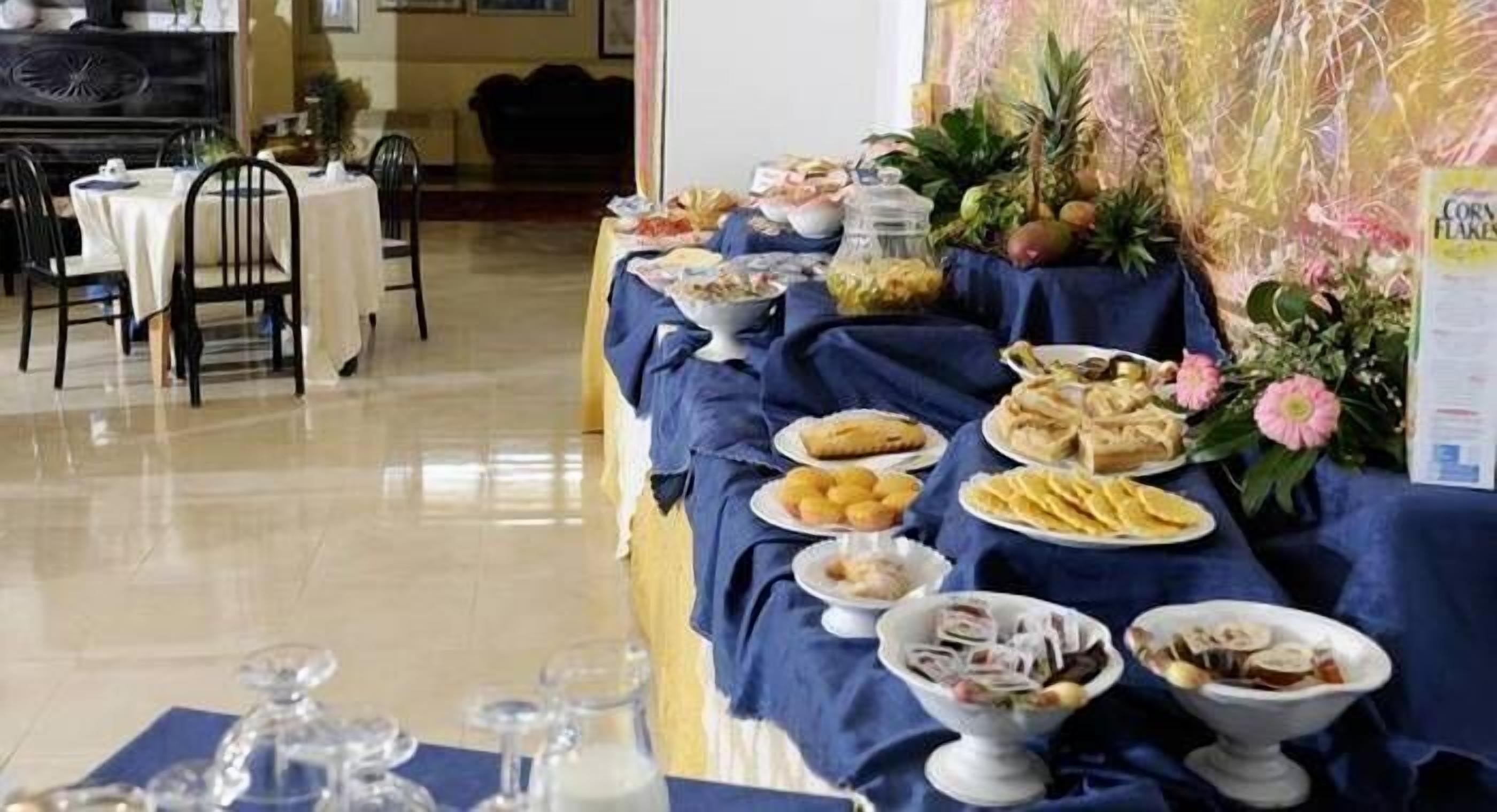 Mesa de buffet com diversos pratos e um arranjo floral.