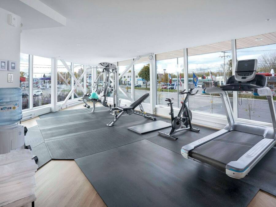 Ginásio com máquinas de cardio, equipamentos de musculação e um dispensador de água.