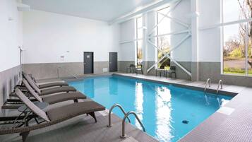 Piscina interior com espreguiçadeiras e escadaria que leva a um andar superior.
