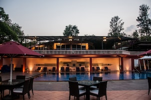Uma área à beira da piscina com espreguiçadeiras, um espaço de estar coberto e a piscina.