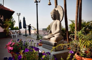Uma estátua de Buda em um jardim, com vasos de plantas e área de estar ao ar livre.