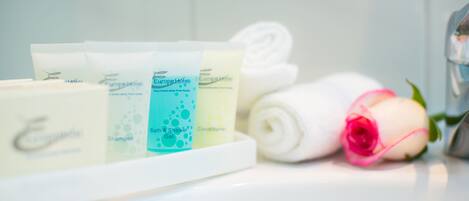 Artigos de higiene pessoal, incluindo shampoo, condicionador e gel de banho, em uma bancada de banheiro.