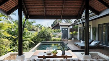 Área externa coberta com piscina, espreguiçadeiras e uma mesa com frutas e uma tigela.