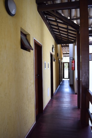 Um corredor com portas de madeira, um extintor de incêndio e um teto com vigas de madeira.