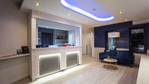 Uma sala de estar moderna com área de bar, um sofá azul e uma mesa de centro redonda.