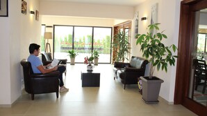 Uma sala de estar espaçosa com uma janela grande, um sofá de couro preto, uma mesa de centro e um vaso com planta.