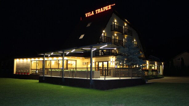 Um hotel com fachada de vidro ampla, varanda e uma placa que diz 'VILA TRAPEZ'.