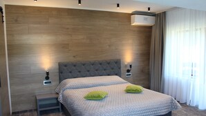 Quarto moderno com uma cama grande, duas mesas de cabeceira e ar condicionado fixado na parede.