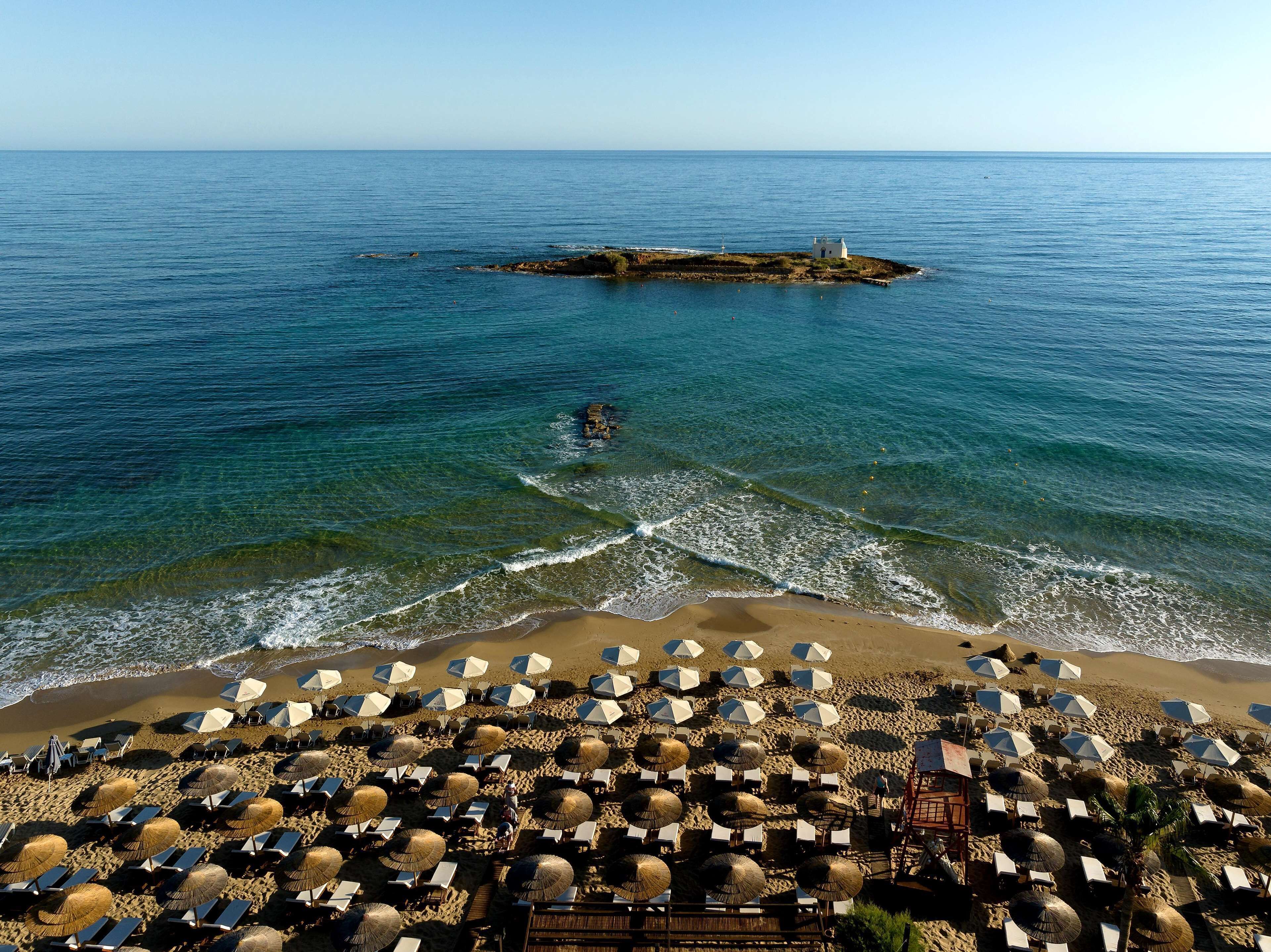 Na praia, areia branca, espreguiçadeiras, guarda-sóis 