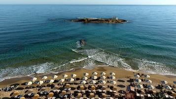 Na praia, areia branca, espreguiçadeiras, guarda-sóis