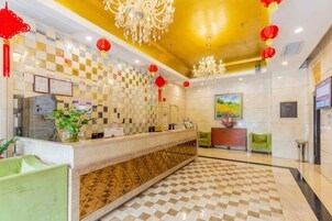 Um saguão de hotel com balcão de recepção, mesa de check-in e piso quadriculado.