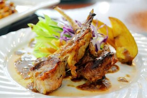 Prato com carne grelhada, legumes e molho.
