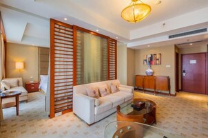 Sala de hotel com sofá, mesa de centro e divisória decorativa.