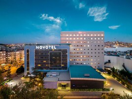Um hotel Novotel com design moderno, vários andares e vista para o horizonte da cidade.