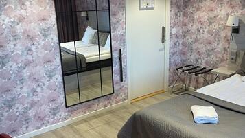 Quarto de hotel com cama, espelho, escrivaninha e cadeira.