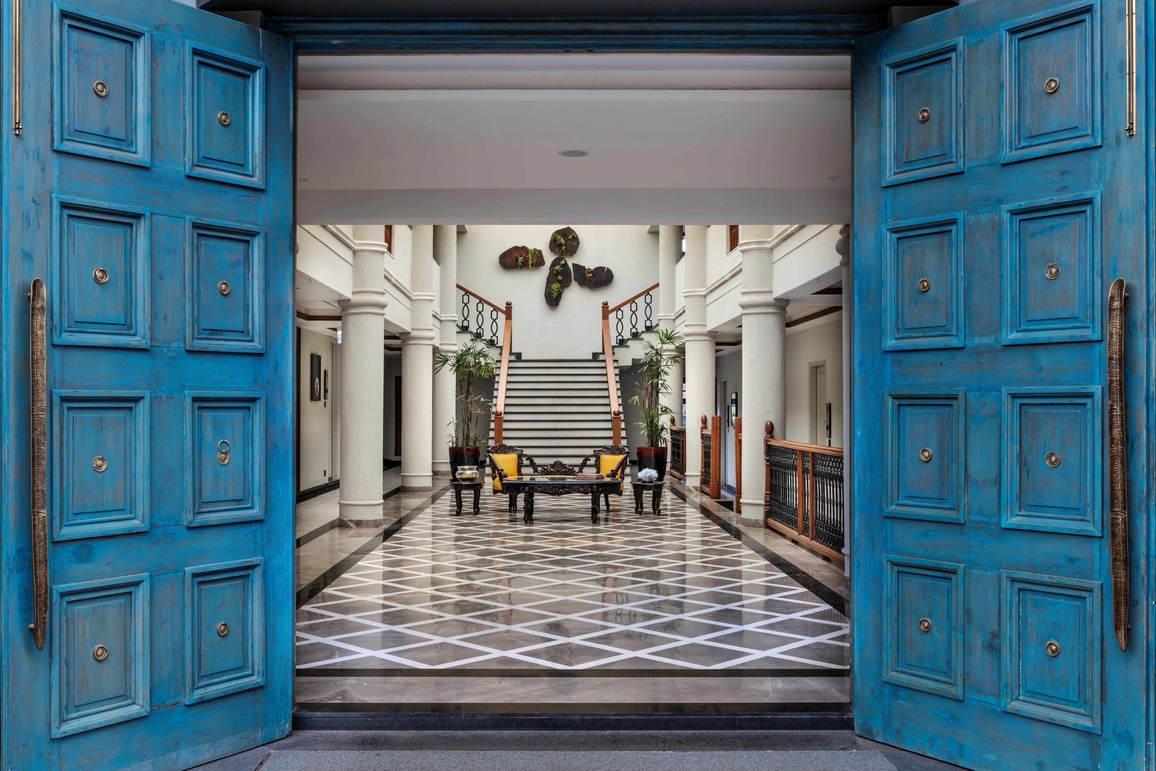 Uma entrada imponente com uma porta azul, uma escadaria e um espaço de estar com piso estampado.