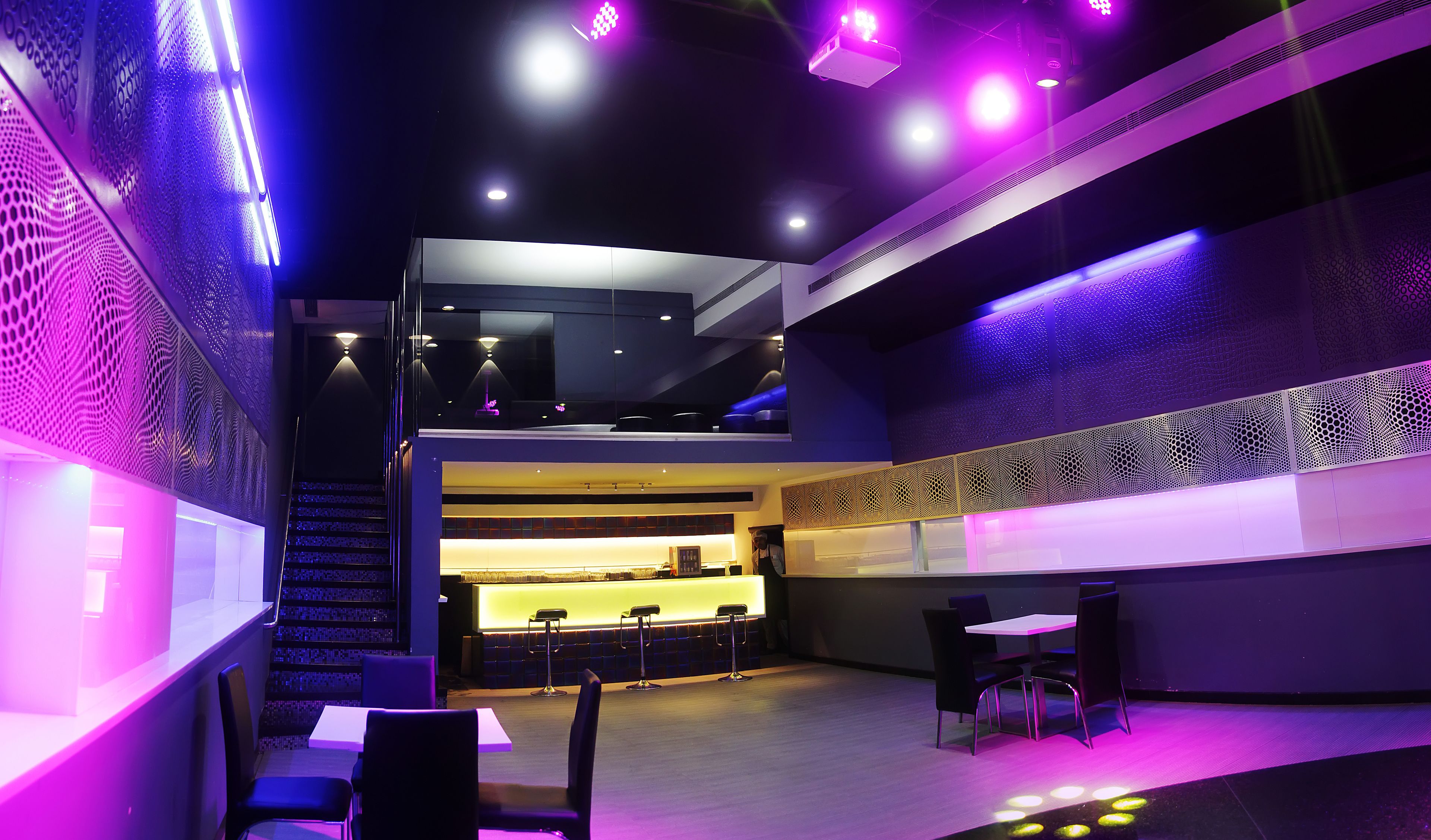 Um interior moderno com área de bar, assentos e escada.