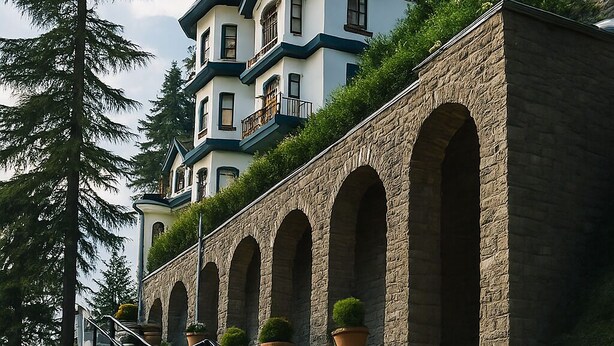 Um edifício de vários andares com fachada de pedra, uma série de arcos e uma escadaria que leva a uma varanda.