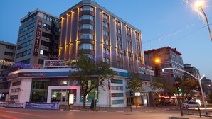 Um hotel de vários andares com design moderno, destacando uma entrada imponente e sinalização para diversas comodidades.