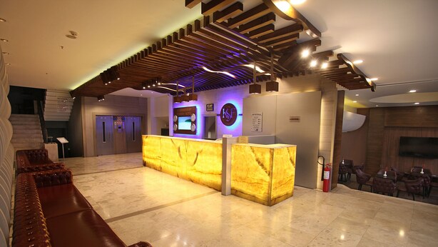 Um lobby moderno com balcão de recepção, área de estar e escadaria.