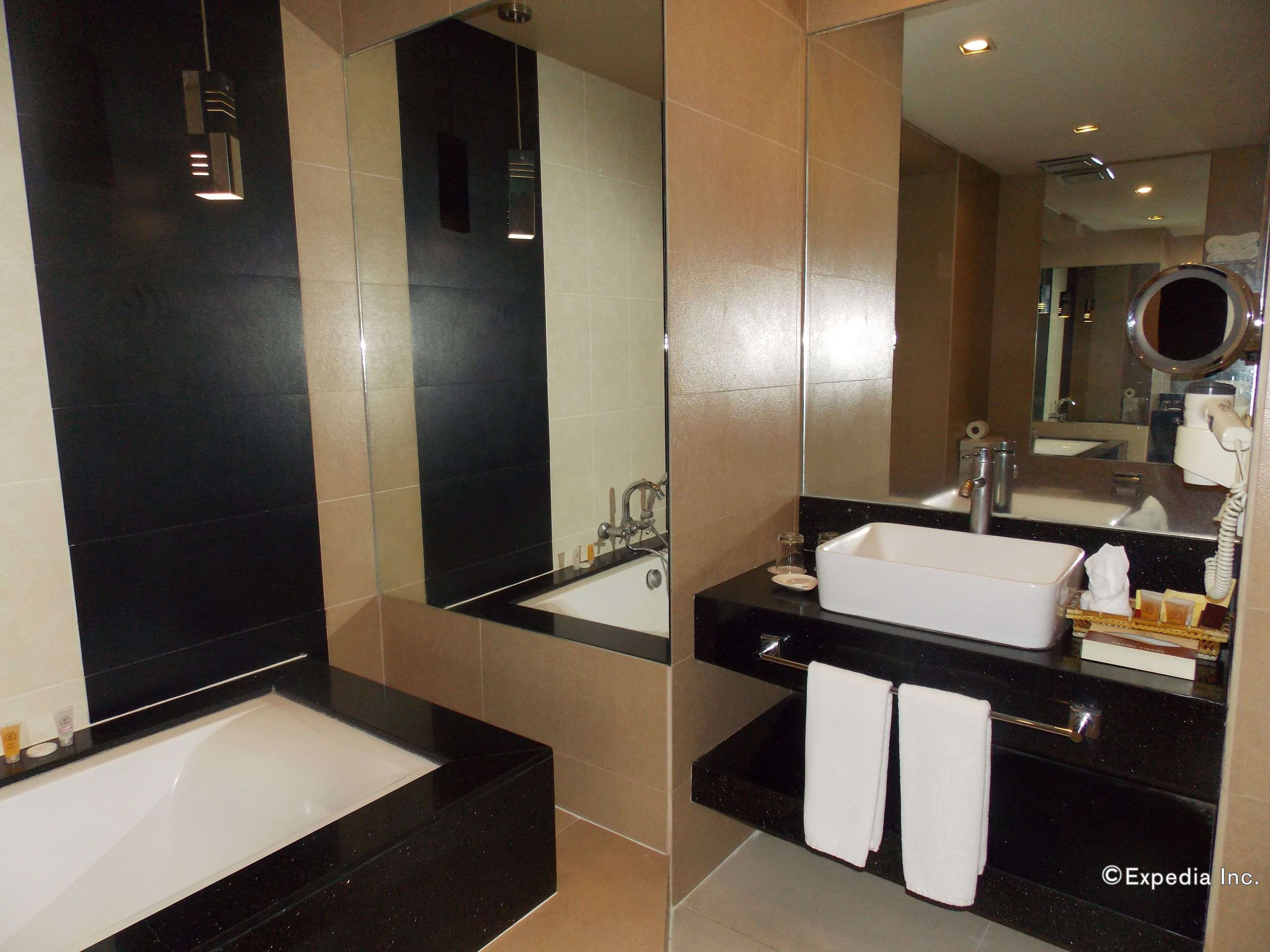 Uma casa de banho moderna com lavatório preto, um espelho grande e uma banheira separada.