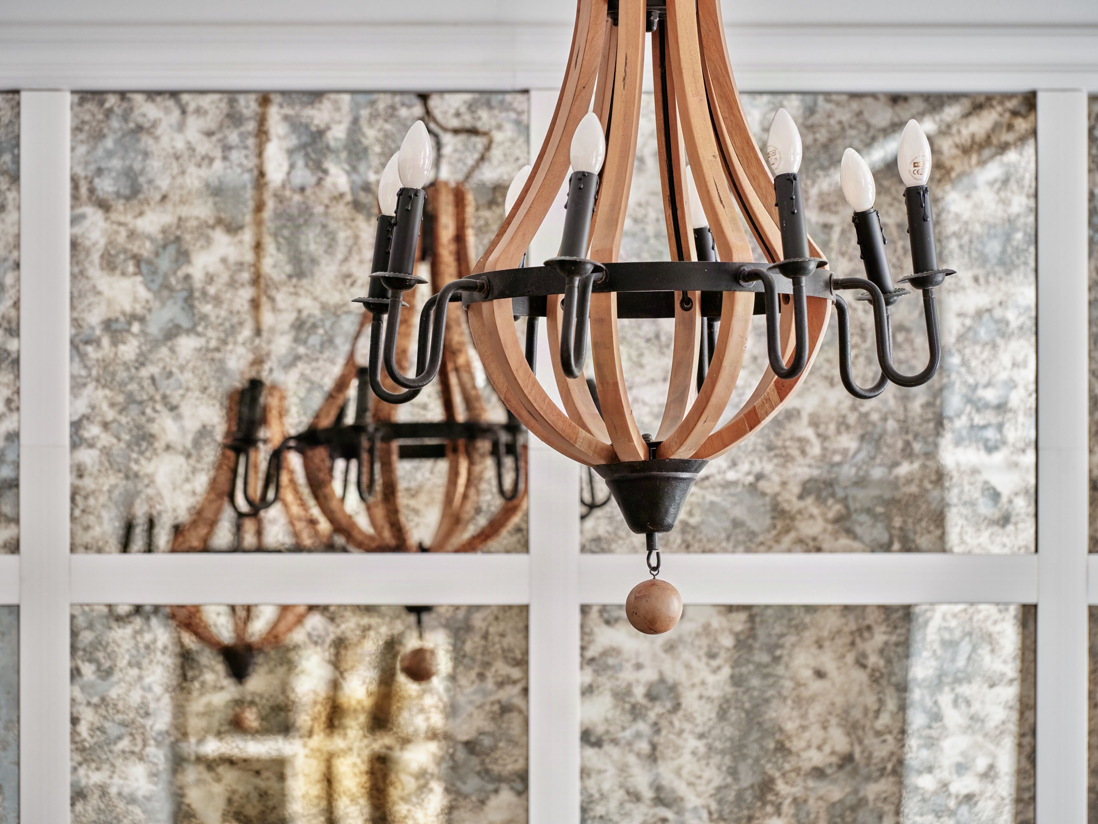 Um candelabro com vários braços e lâmpadas, pendurado em frente a uma parede texturizada.