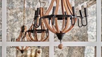 Um candelabro com vários braços e lâmpadas, pendurado em frente a uma parede texturizada.
