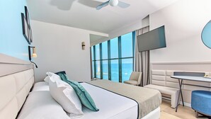 Quarto de hotel moderno com uma cama grande, uma mesa de trabalho, uma cadeira e uma TV fixada na parede.