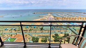 Uma varanda com vista para uma marina, praia e área urbana.