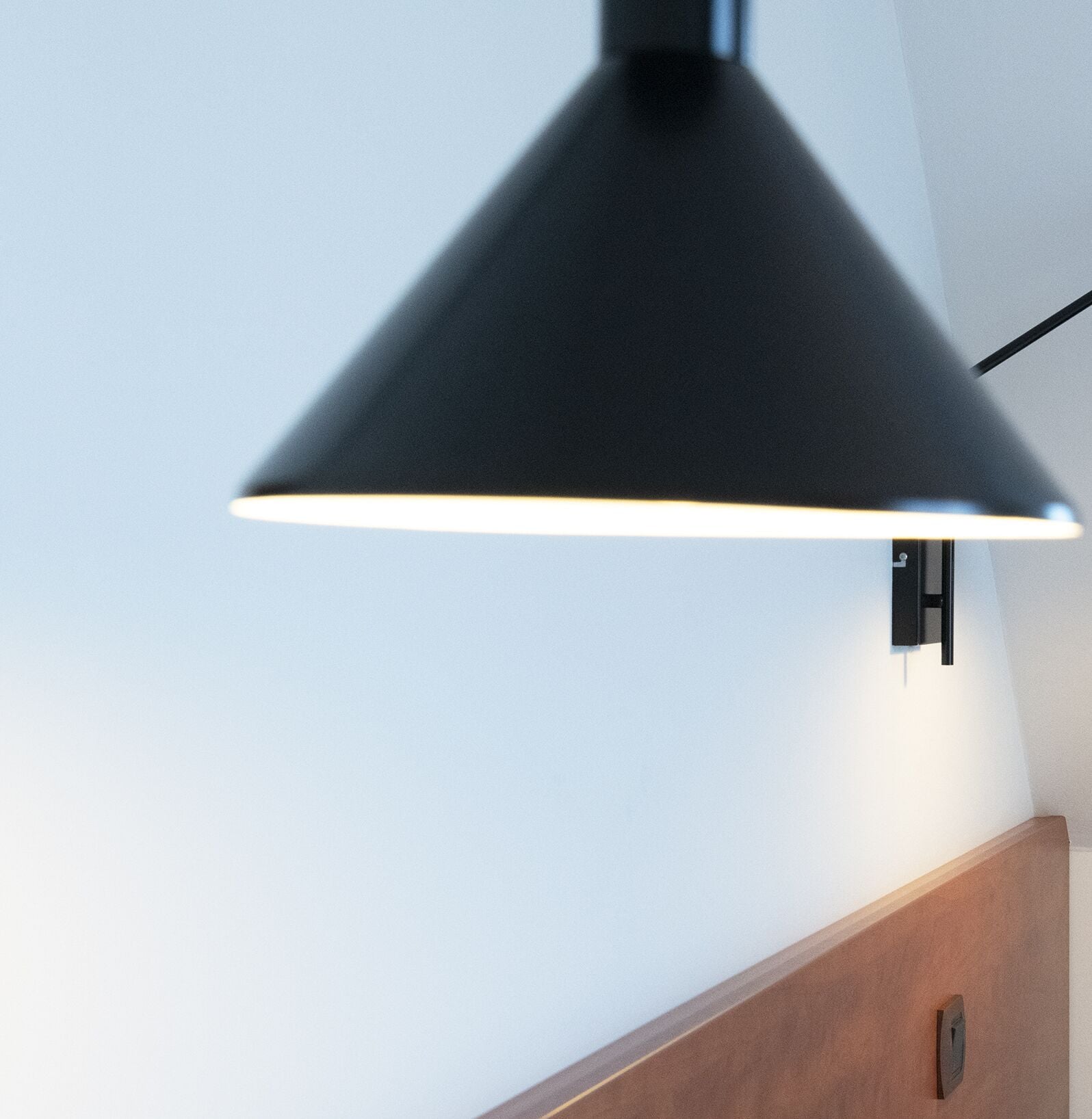 Uma luminária pendente moderna com cúpula preta e fonte de luz branca.