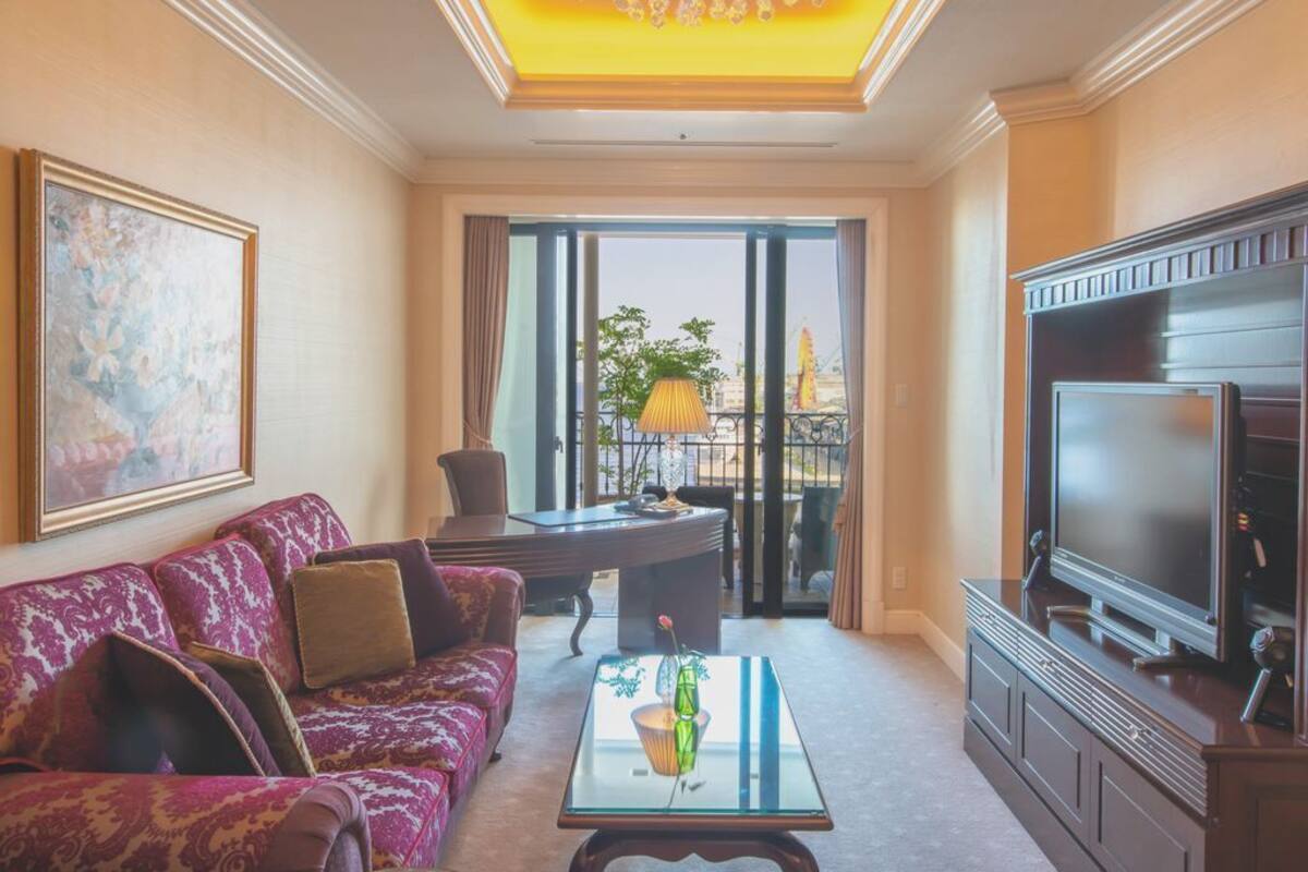 Sala de estar com sofá, mesa de centro, televisão e varanda com vista.