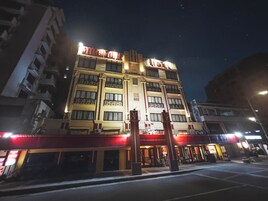 Um hotel com vários andares, sinalização iluminada, varandas e entrada no nível da rua.