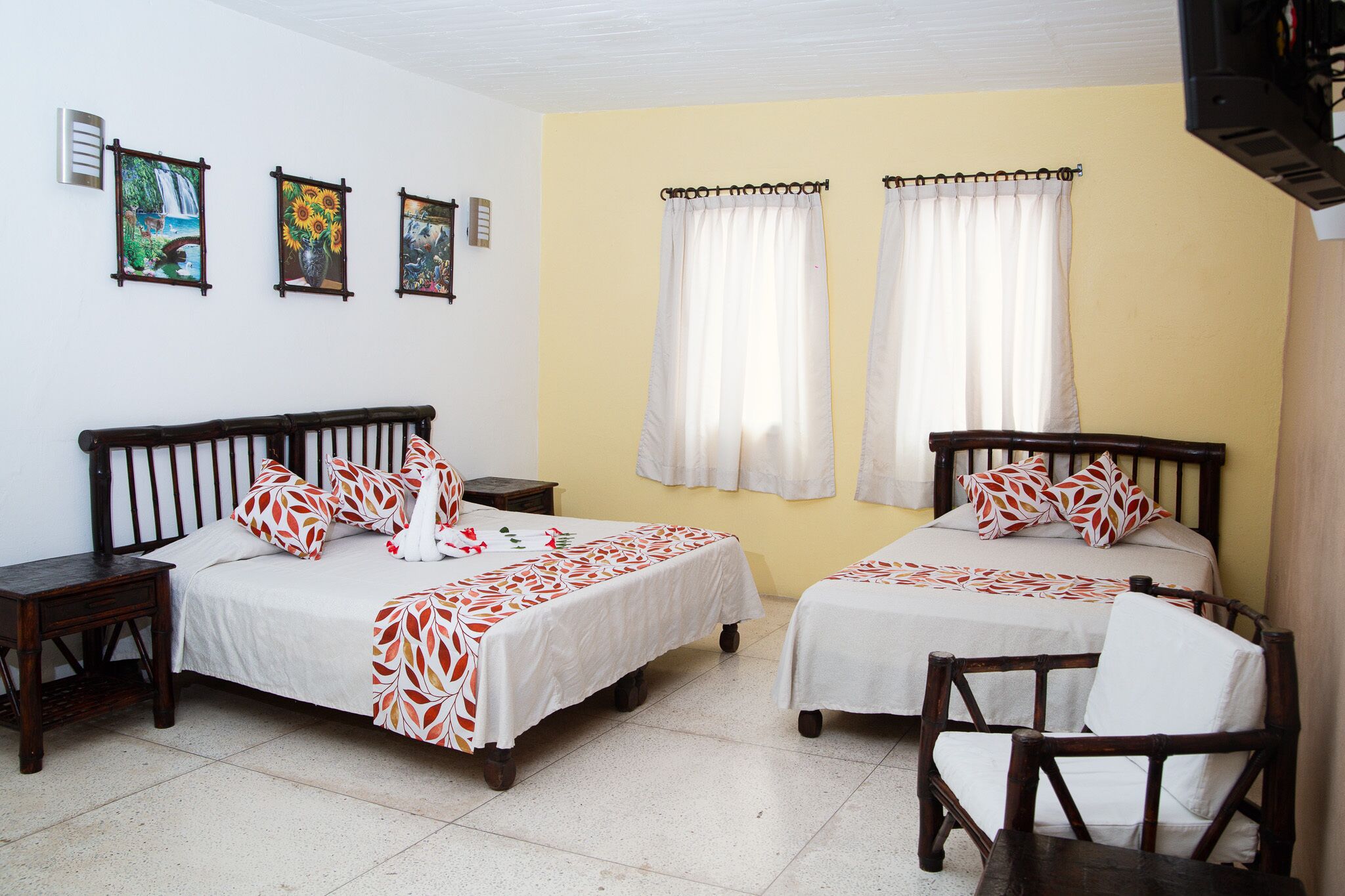 Quarto com duas camas, cabeceira de madeira, uma pequena mesa e uma cadeira.