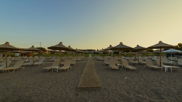 Na praia, espreguiçadeiras, guarda-sóis, toalhas de praia