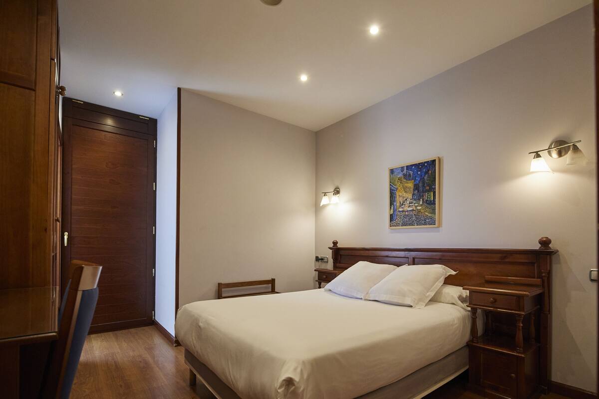 Quarto com uma cama grande, cabeceira de madeira, mesas de cabeceira e um quadro na parede.