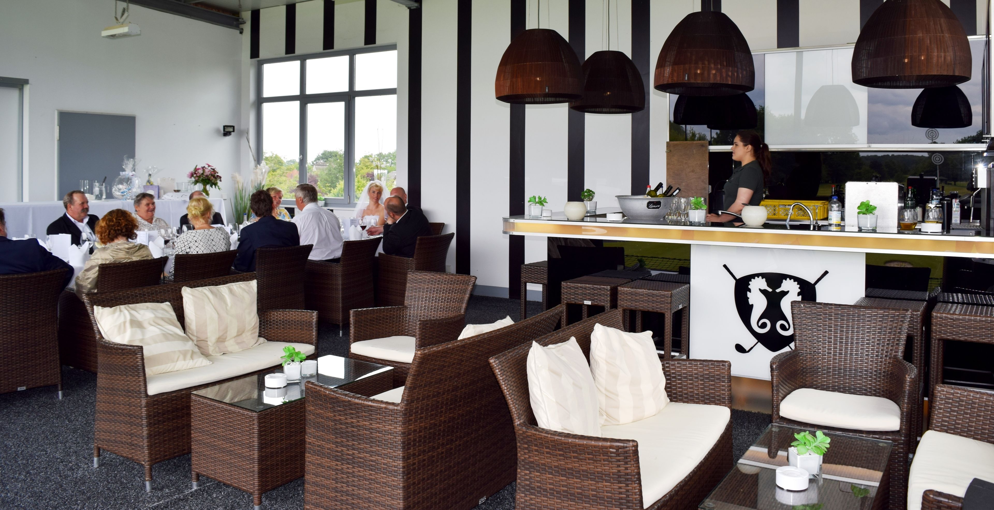 Restaurante com mobiliário de vime e iluminação pendente.