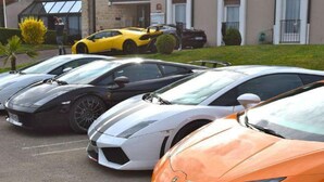 Uma fileira de carros esportivos de luxo estacionados em uma entrada de garagem.