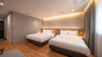 Quarto de hotel moderno com duas camas, piso de madeira e cores neutras.