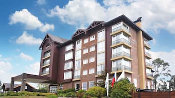 Um hotel com vários andares, fachada de tijolos, varandas e entrada coberta.