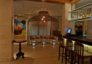 Uma área de bar com um sofá curvo, mesas redondas e cadeiras de madeira.