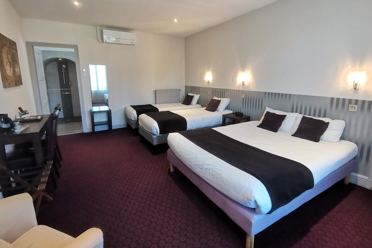 Quarto de hotel com duas camas, uma mesa de trabalho e área de chuveiro.