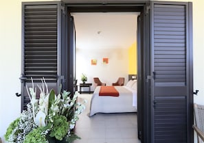 Quarto de hotel com cama, mesa de cabeceira, planta em vaso e vista para o exterior.